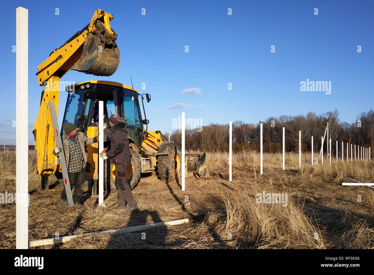 The excavator with the bucket clogs the iron pillars for the fence in ...