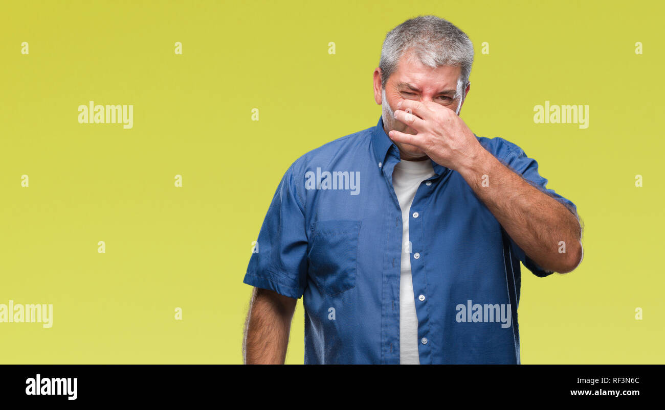 Handsome senior man over isolated background smelling something stinky ...