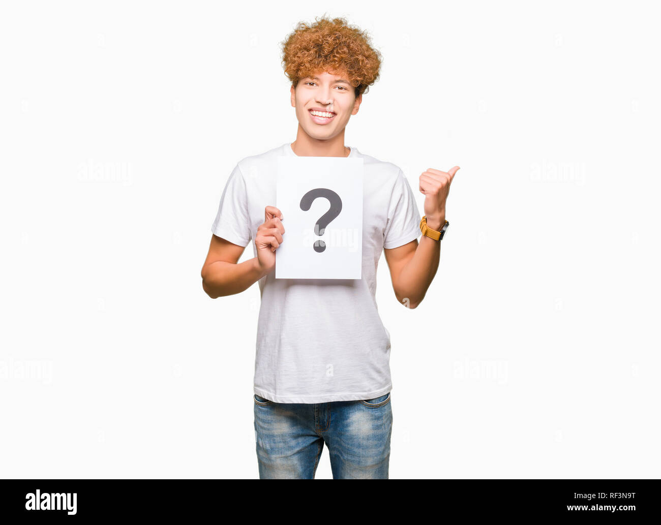 Young handsome man holding paper with question mark pointing and ...