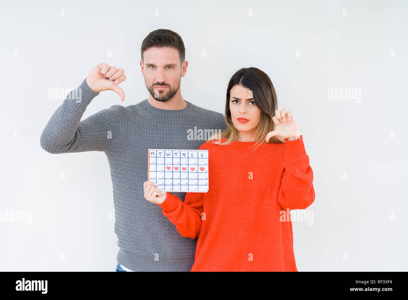 Young couple holding ovulation calendar over isolated background with ...