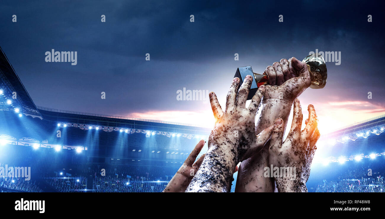 Hand of athlete holding cup trophy against stadium. Mixed media Stock ...