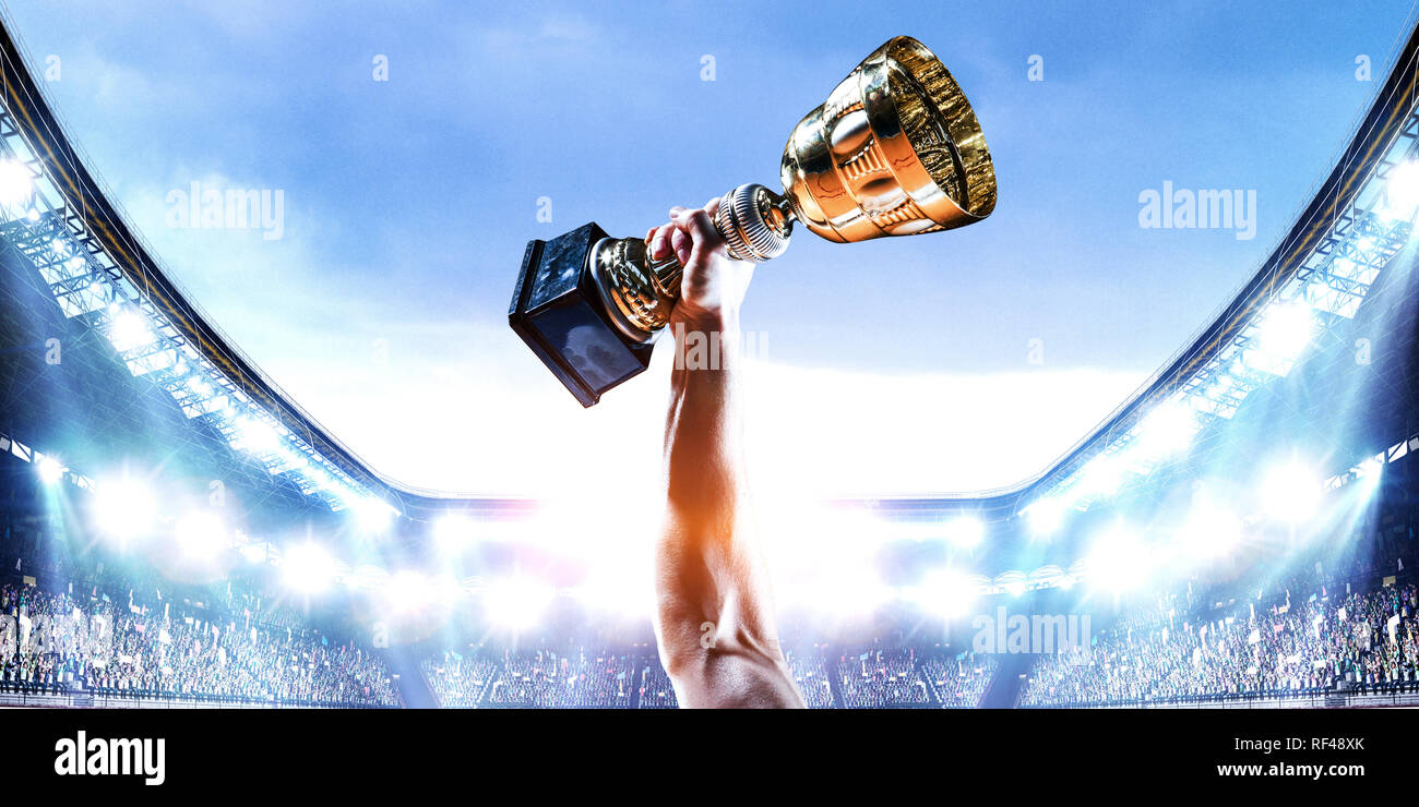 Hand of athlete holding cup trophy against stadium. Mixed media Stock ...