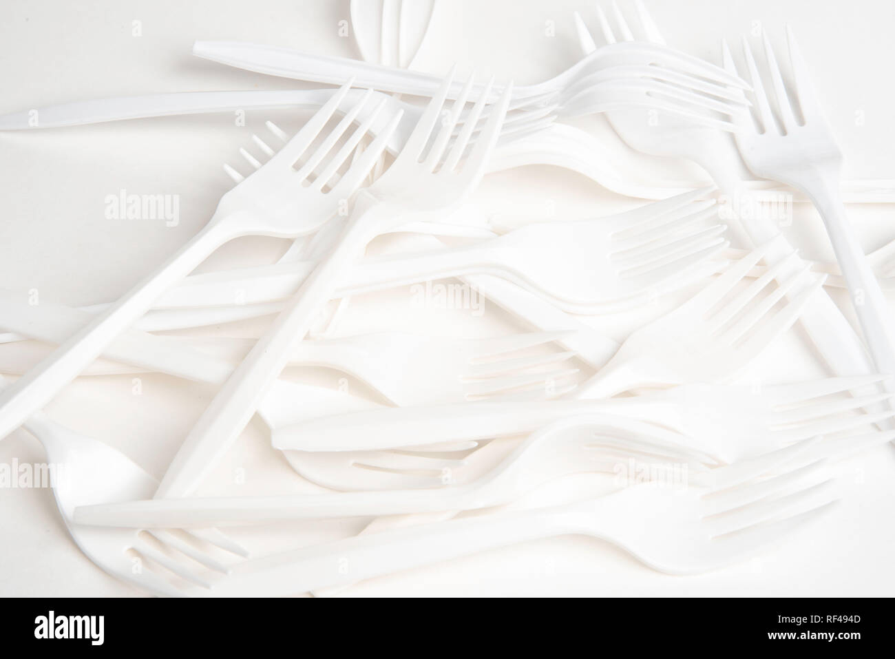 A bunch of white disposable single-use plastic forks commonly available ...