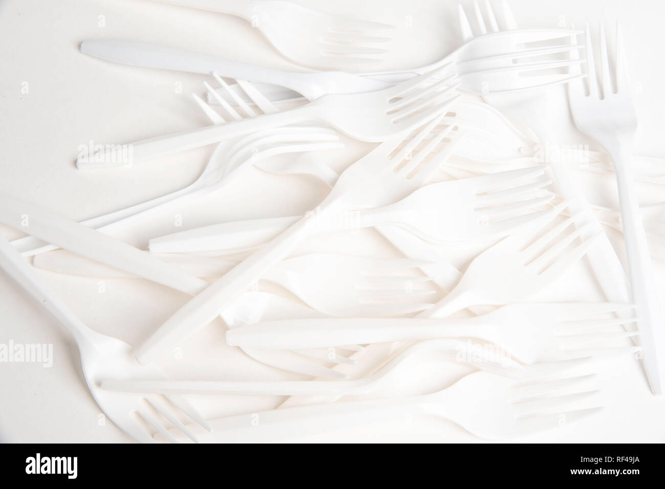 A bunch of white disposable single-use plastic forks commonly available ...