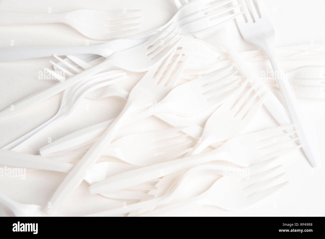 A bunch of white disposable single-use plastic forks commonly available ...