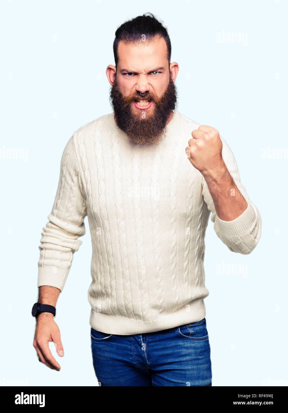 Young hipster man wearing winter sweater angry and mad raising fist ...