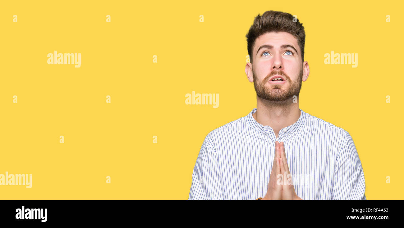 Young handsome man begging and praying with hands together with hope ...