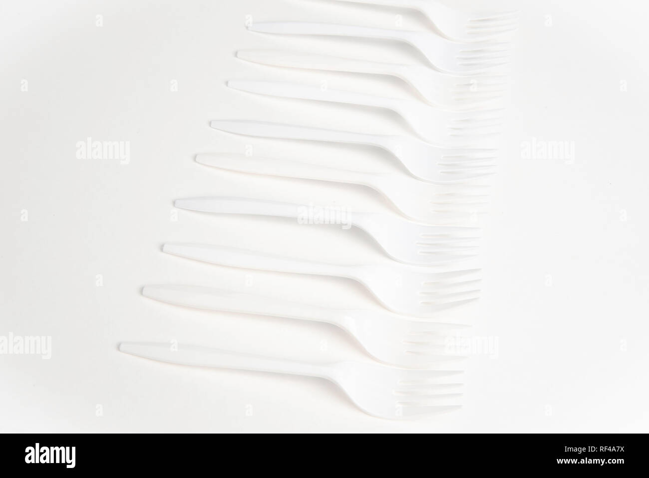 A bunch of white disposable single-use plastic forks commonly available ...