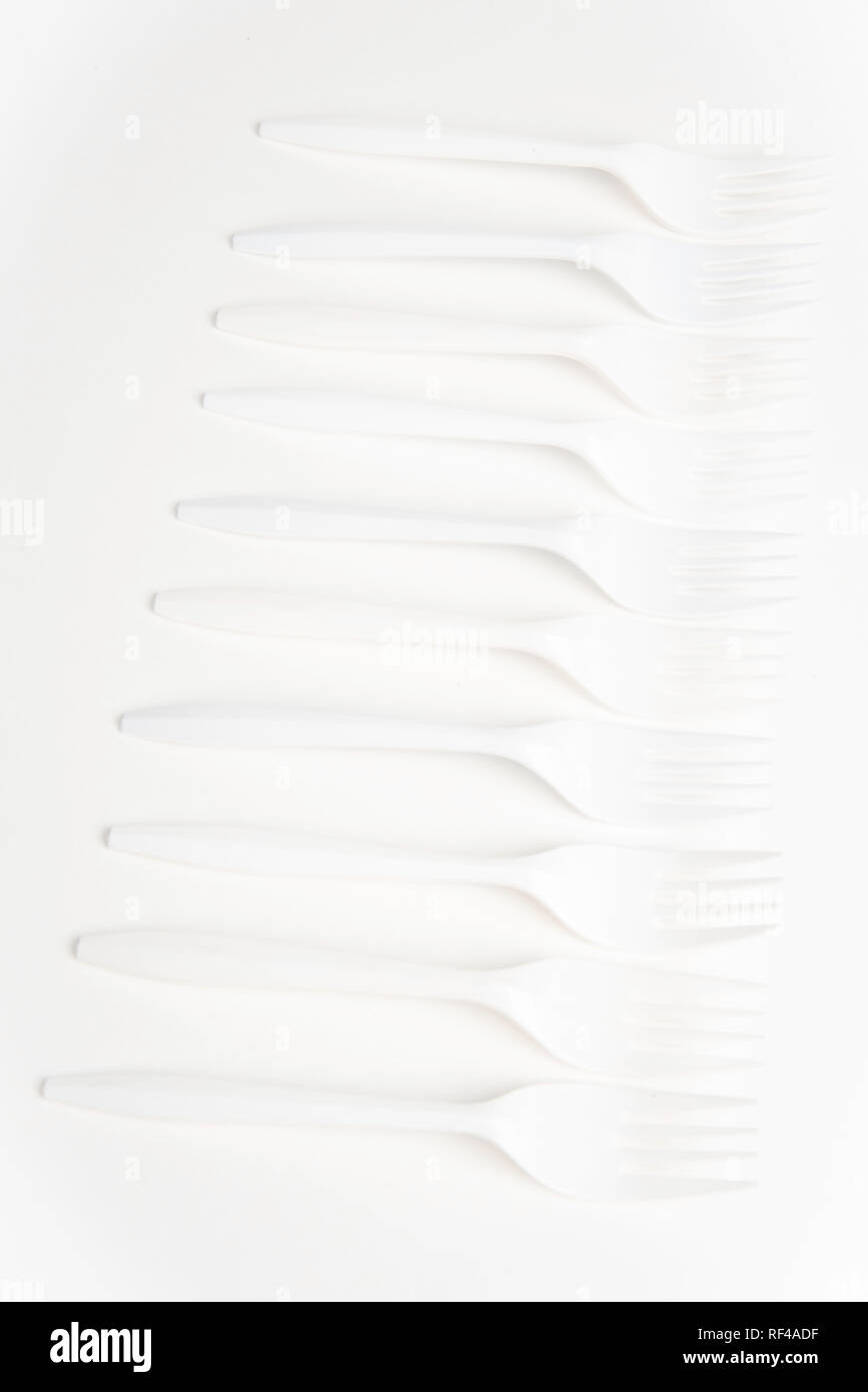 A bunch of white disposable single-use plastic forks commonly available ...