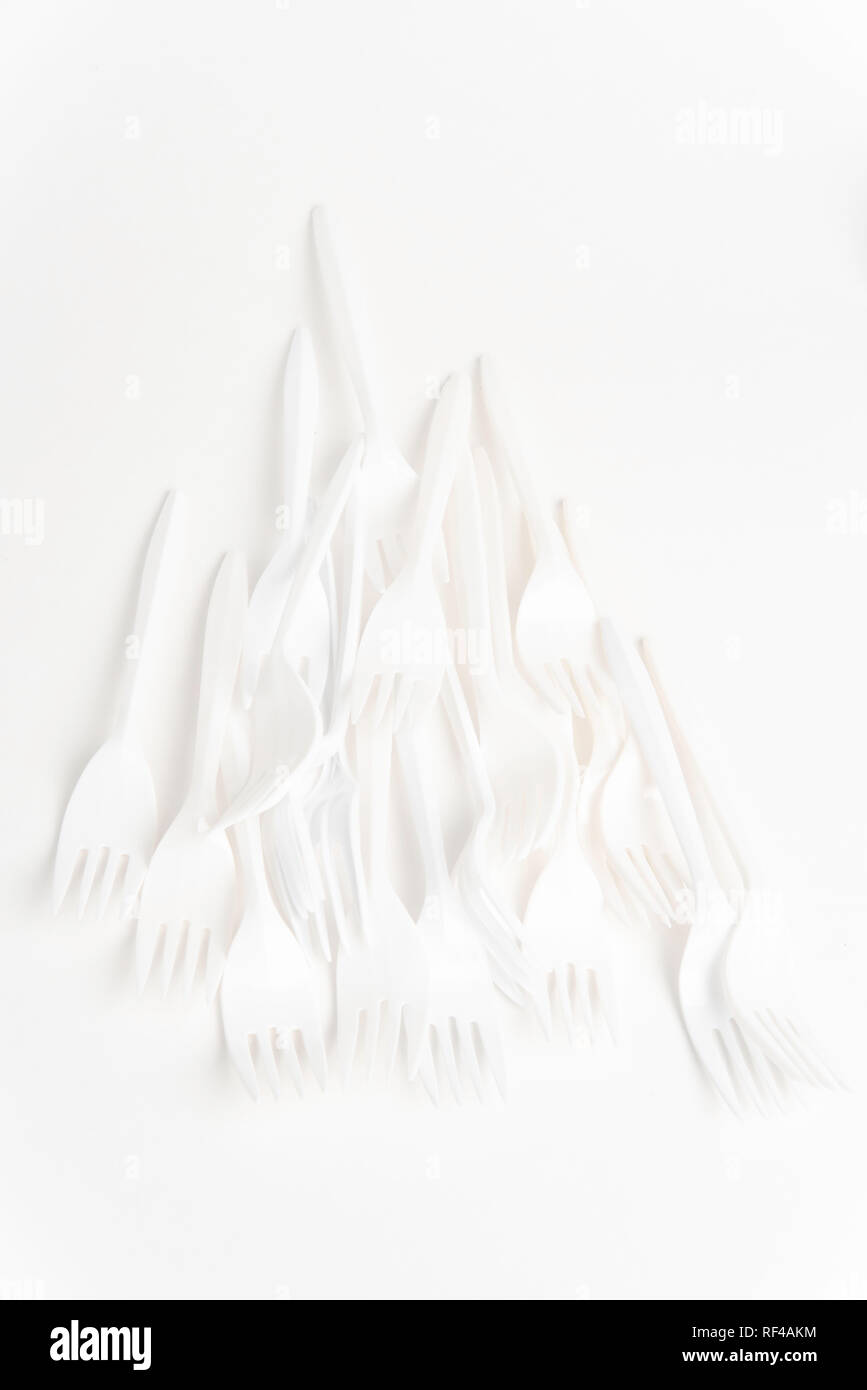A bunch of white disposable single-use plastic forks commonly available ...