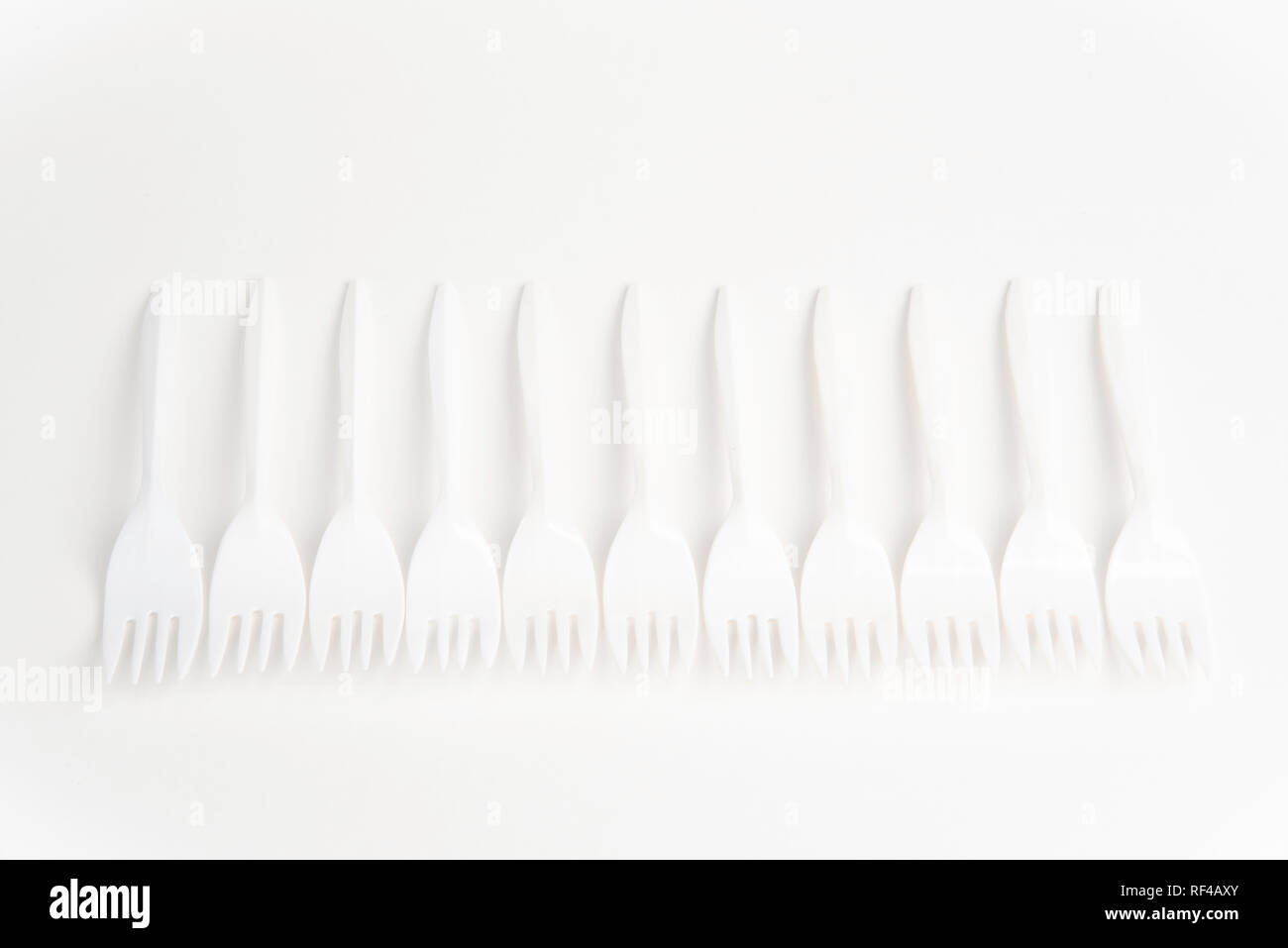 A bunch of white disposable single-use plastic forks commonly available ...