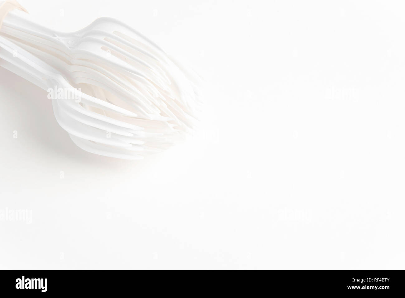 A bunch of white disposable single-use plastic forks commonly available ...