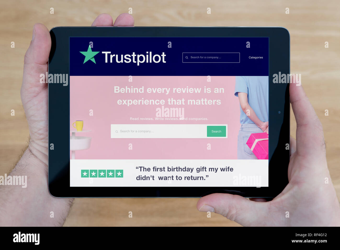 A man looks at the Trustpilot website on his iPad tablet device, shot ...