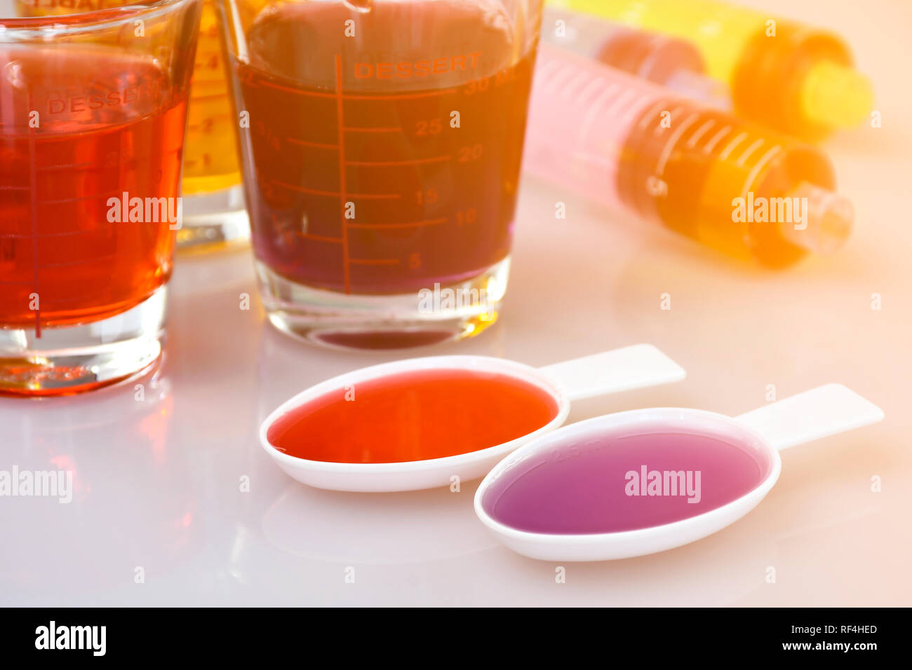 Medicinal cup, oral syringe and teaspoon filled with oral syrup ...