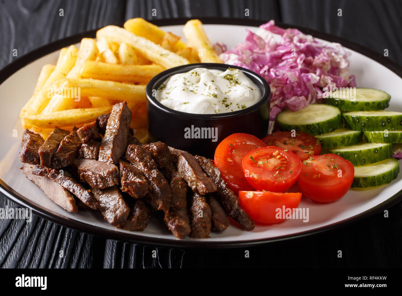 Beef Doner kebab on a plate with french fries, salad and sauce close-up ...