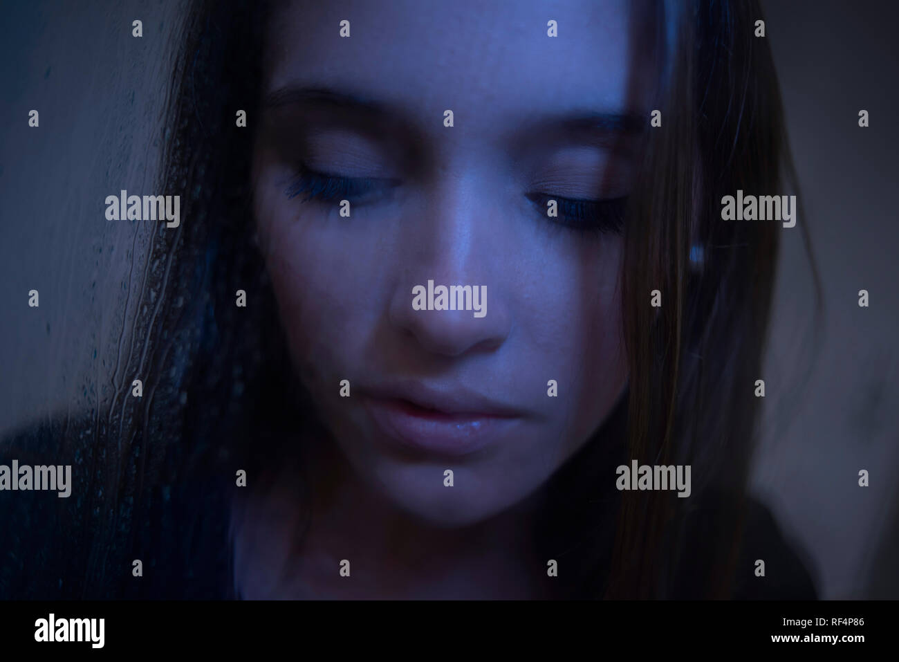 Beautiful young caucasian woman behind a window through the glass with ...