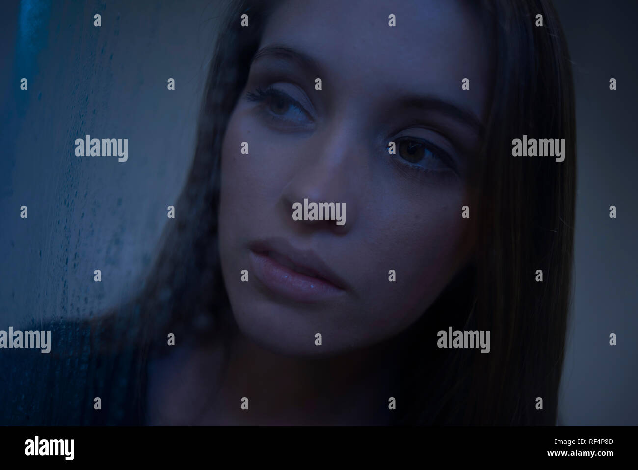 Beautiful young caucasian woman behind a window through the glass with ...