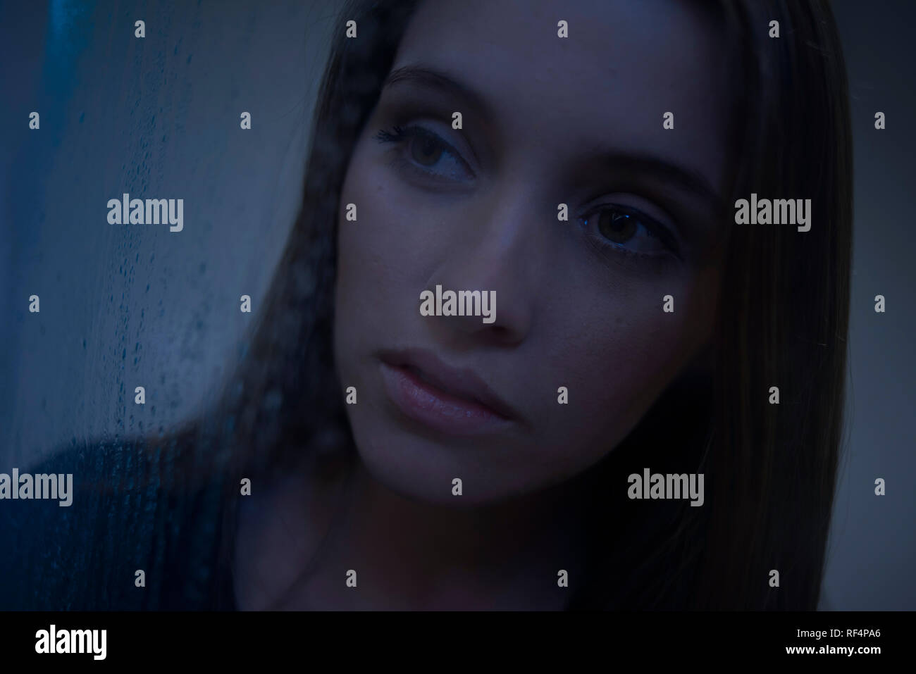 Beautiful young caucasian woman behind a window through the glass with ...