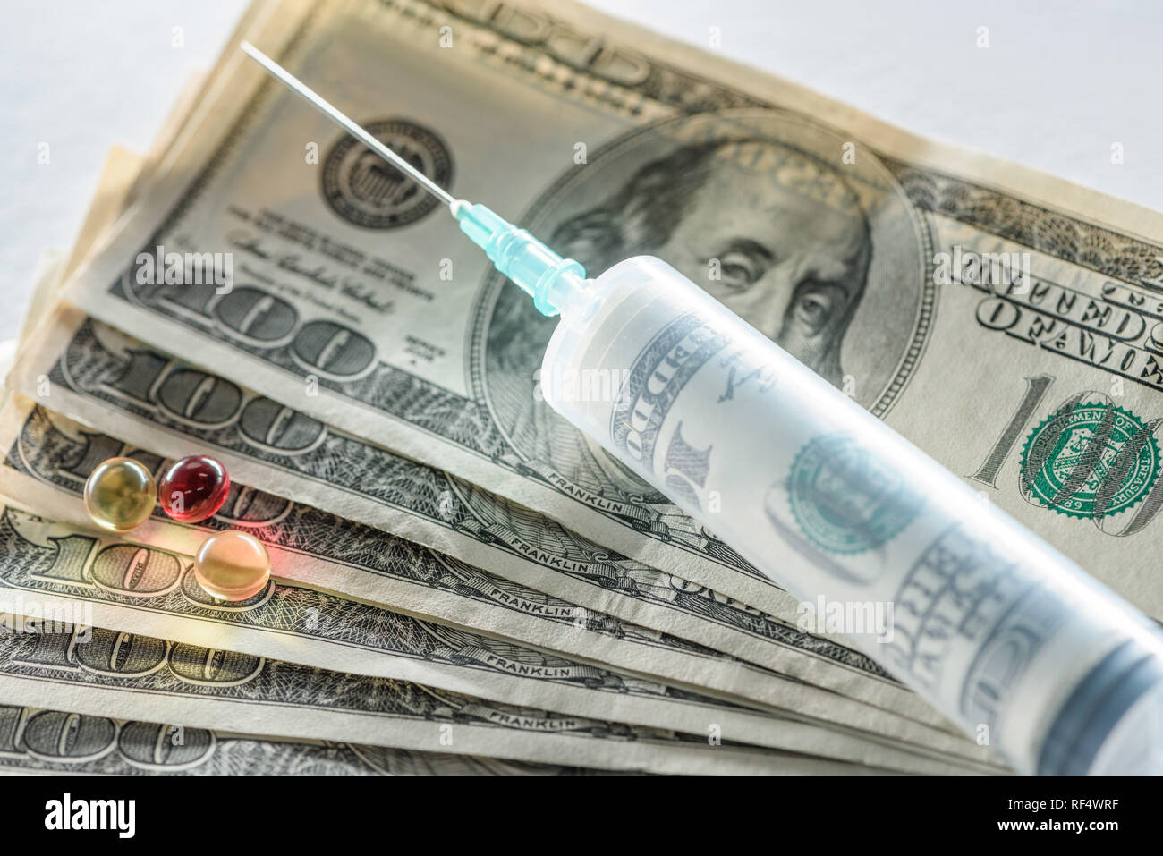 close up of syringe with money injection and pills on dollar banknotes ...
