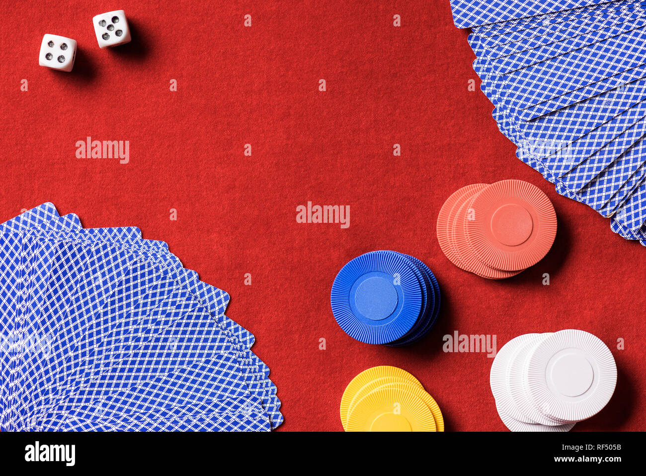 top view of red poker table with multicolored chips, dices and unfolded ...