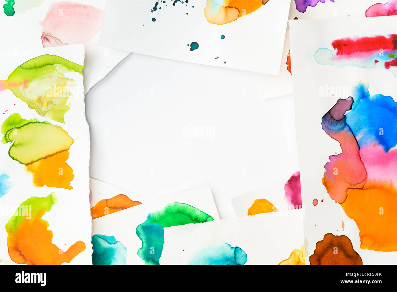 top view of frame with abstract watercolor spills on papers on white ...