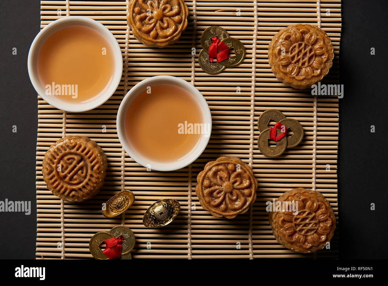 top view of mooncakes, feng shui coins and tea pot with cups on bamboo ...