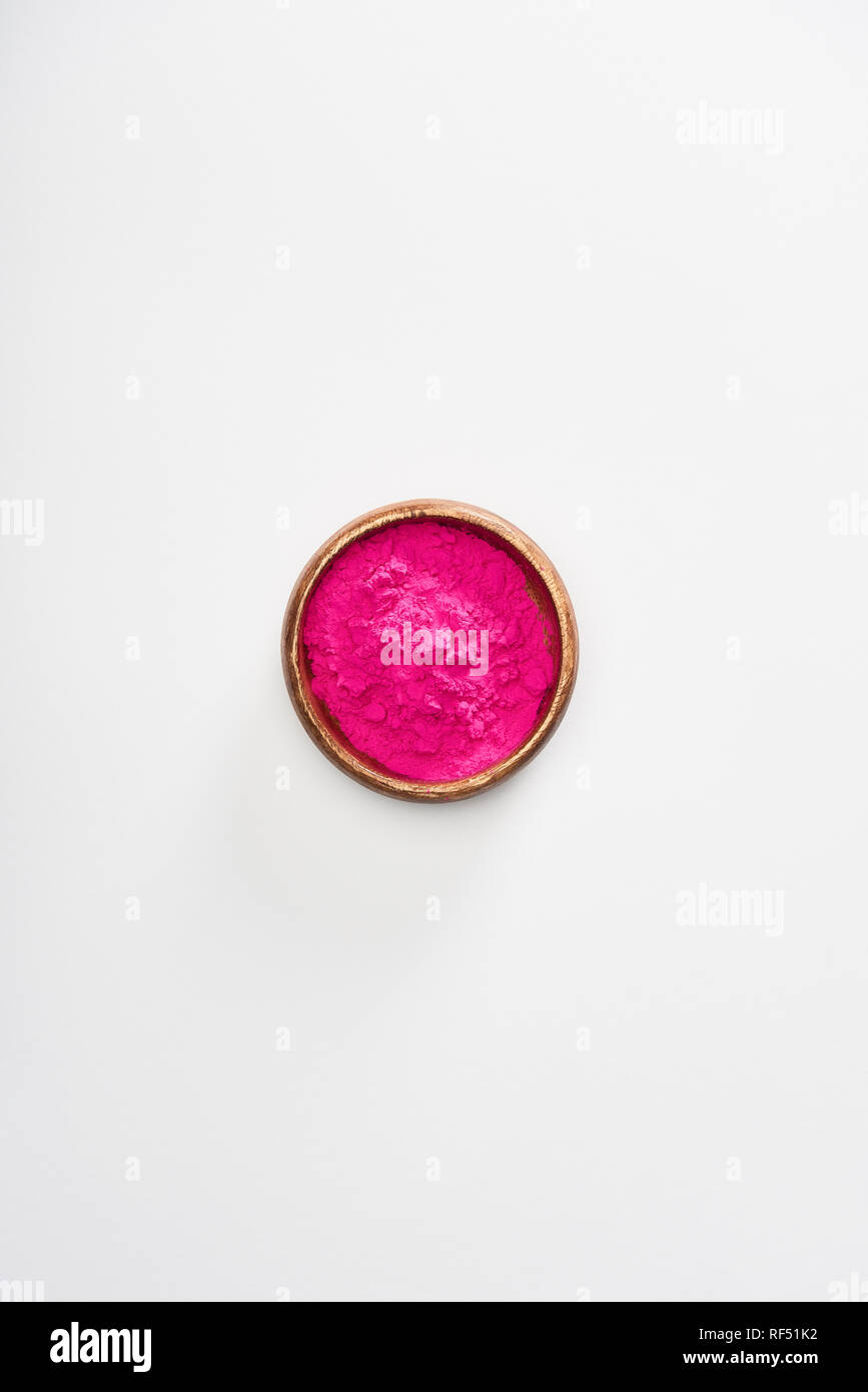 top view of wooden bowl with pink holi powder on white background Stock ...
