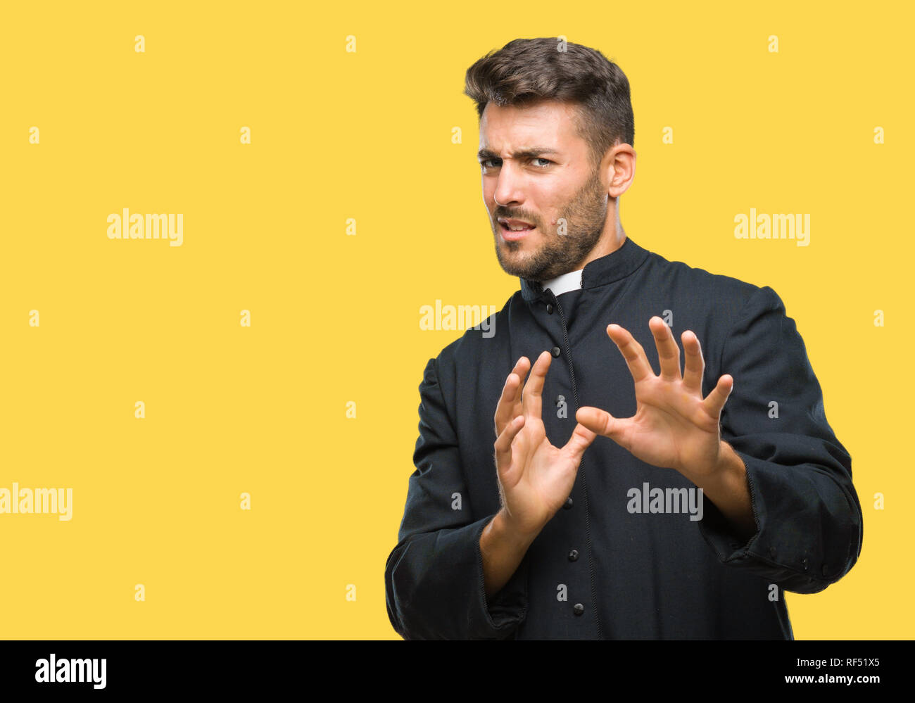 Young catholic christian priest man over isolated background disgusted ...
