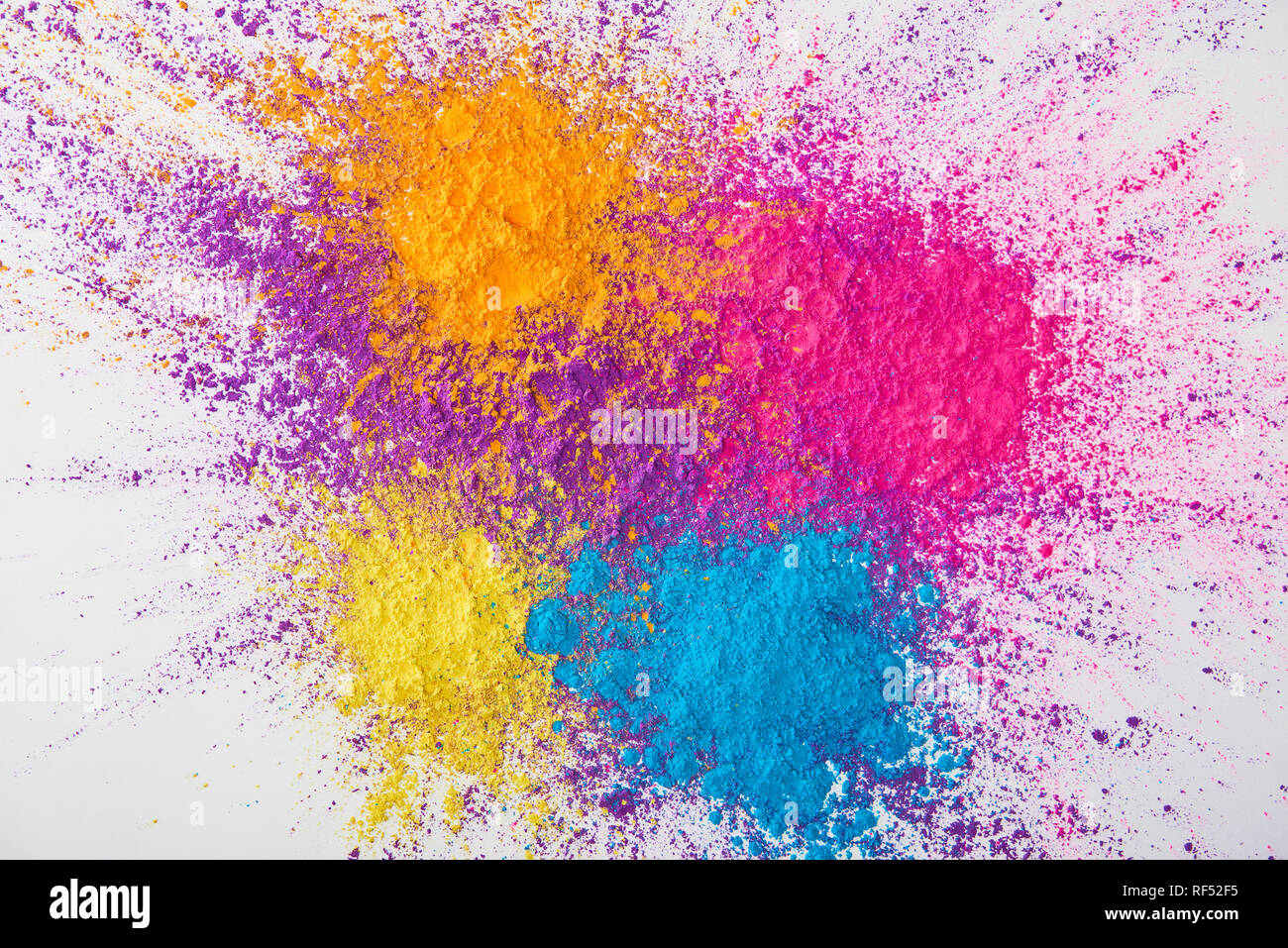 top view of explosion of multicolored holi powder on white background ...