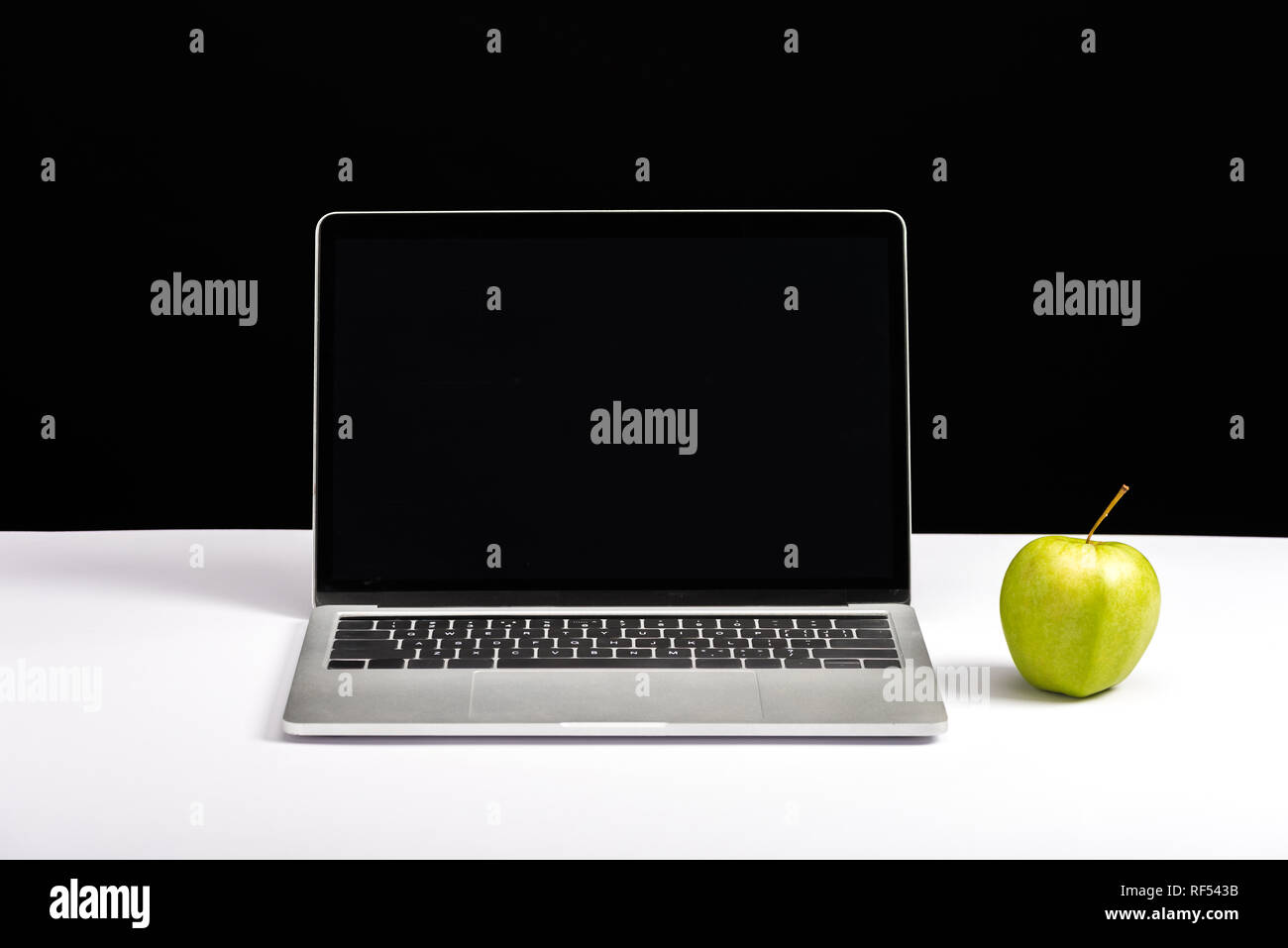 apple and laptop with blank screen on desk isolated on black Stock ...