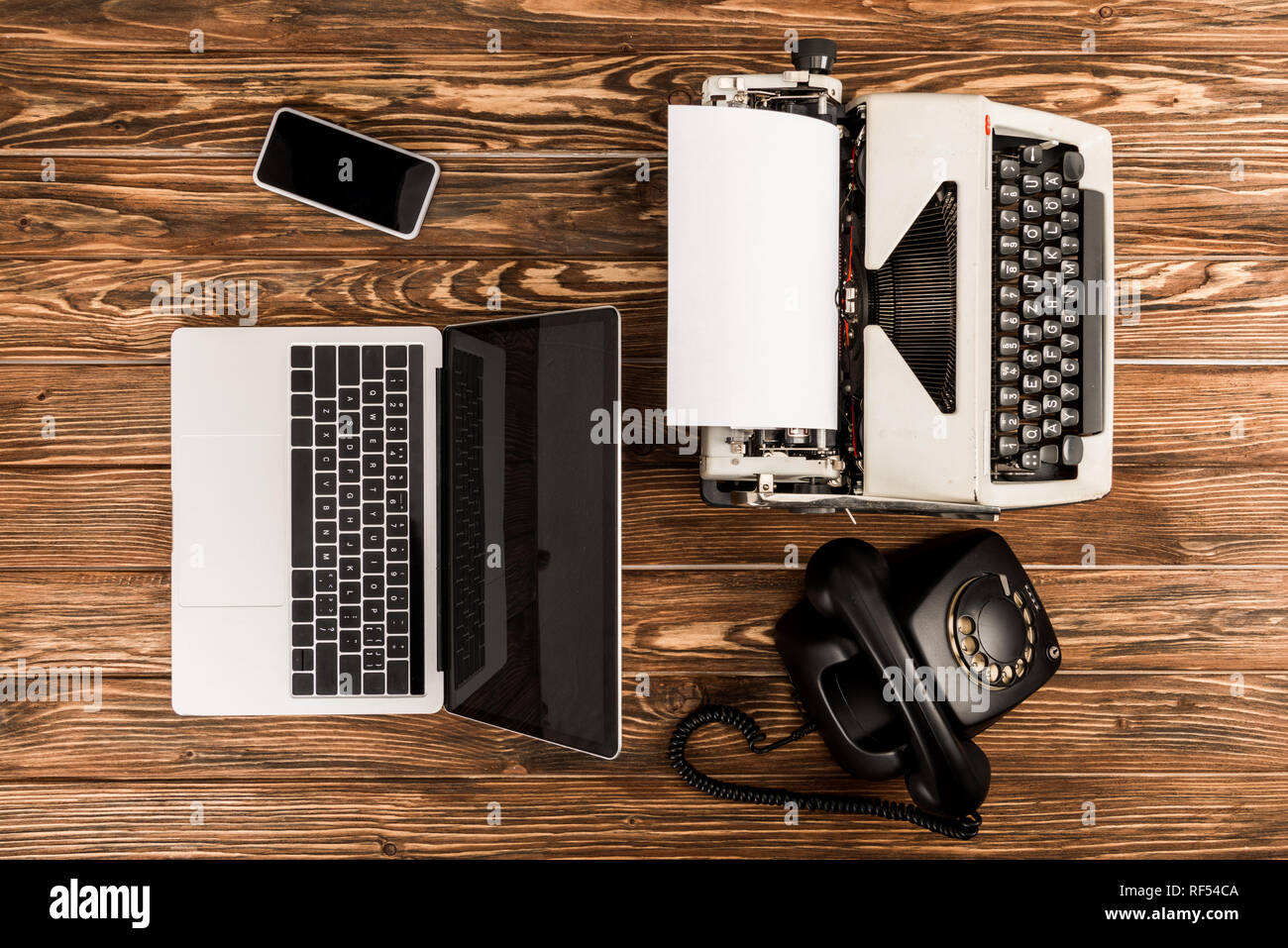 top view of typewriter, laptop, rotary dial telephone and smartphone on ...
