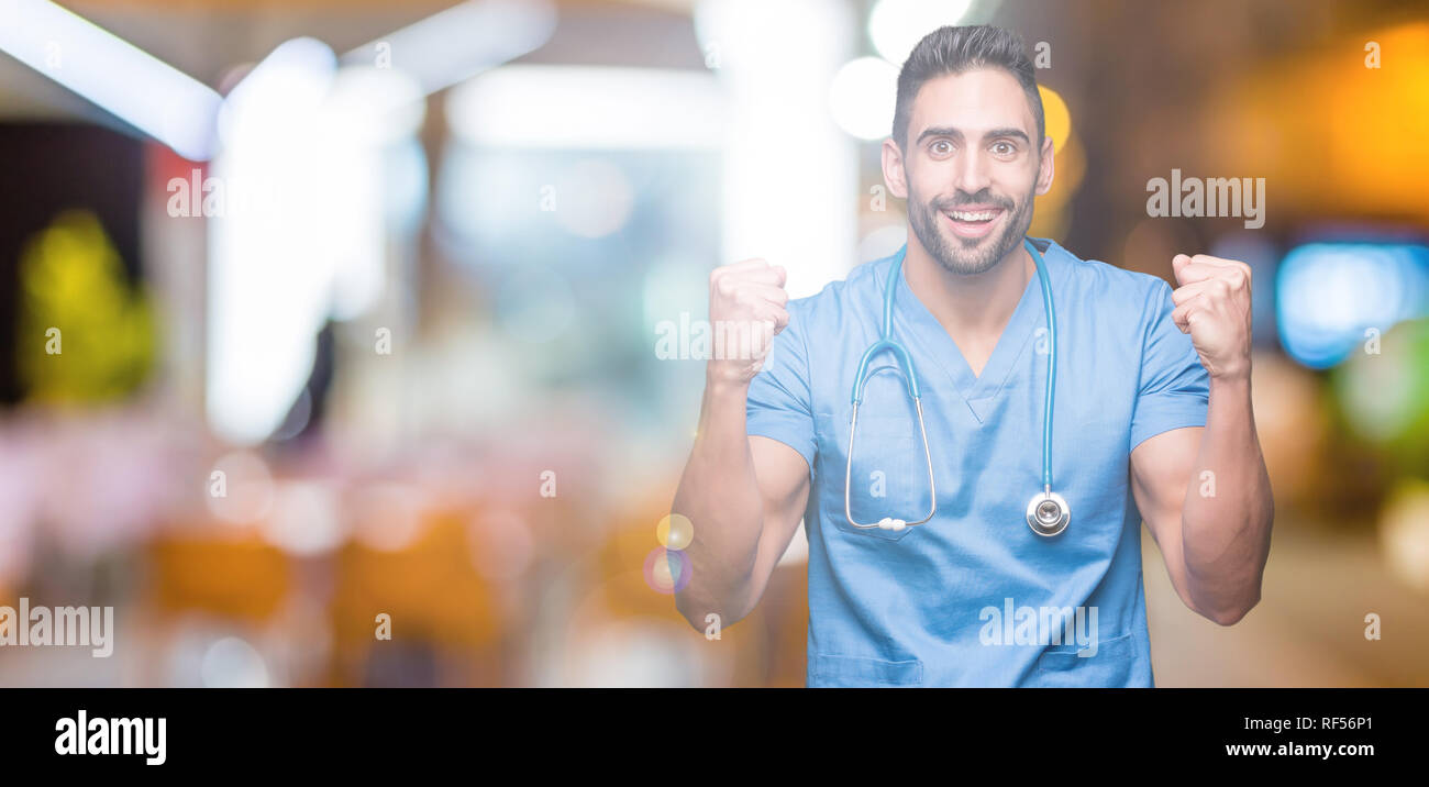 Handsome young doctor surgeon man over isolated background celebrating ...