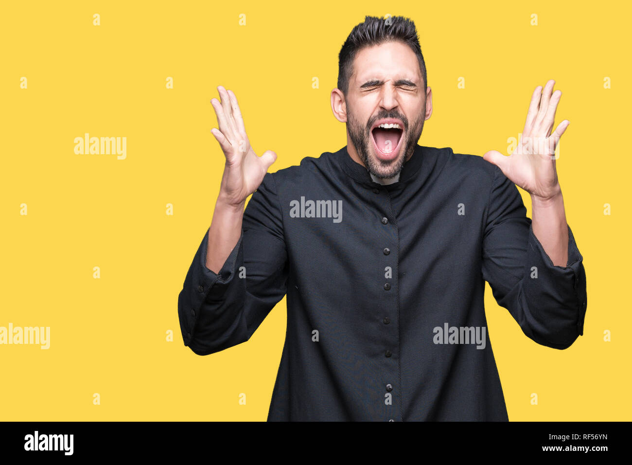 Young Christian priest over isolated background celebrating mad and ...