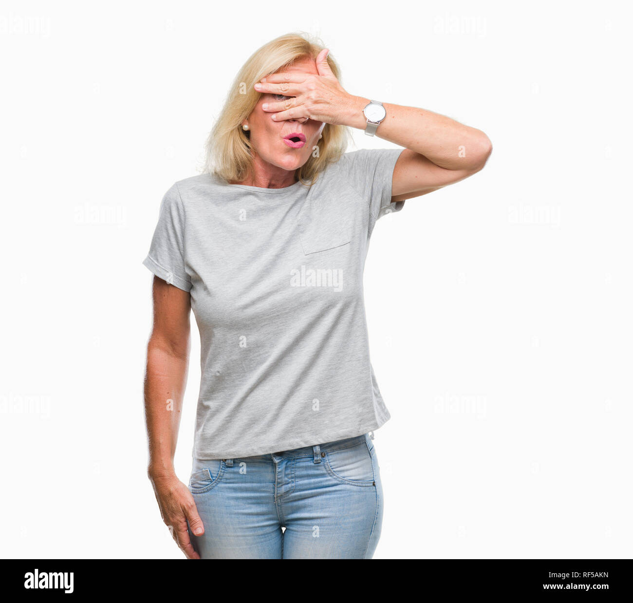 Middle age blonde woman over isolated background peeking in shock covering face and eyes with ...