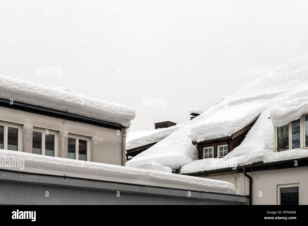 Roof of building with window and thick snow layer in winter. Snowfall ...