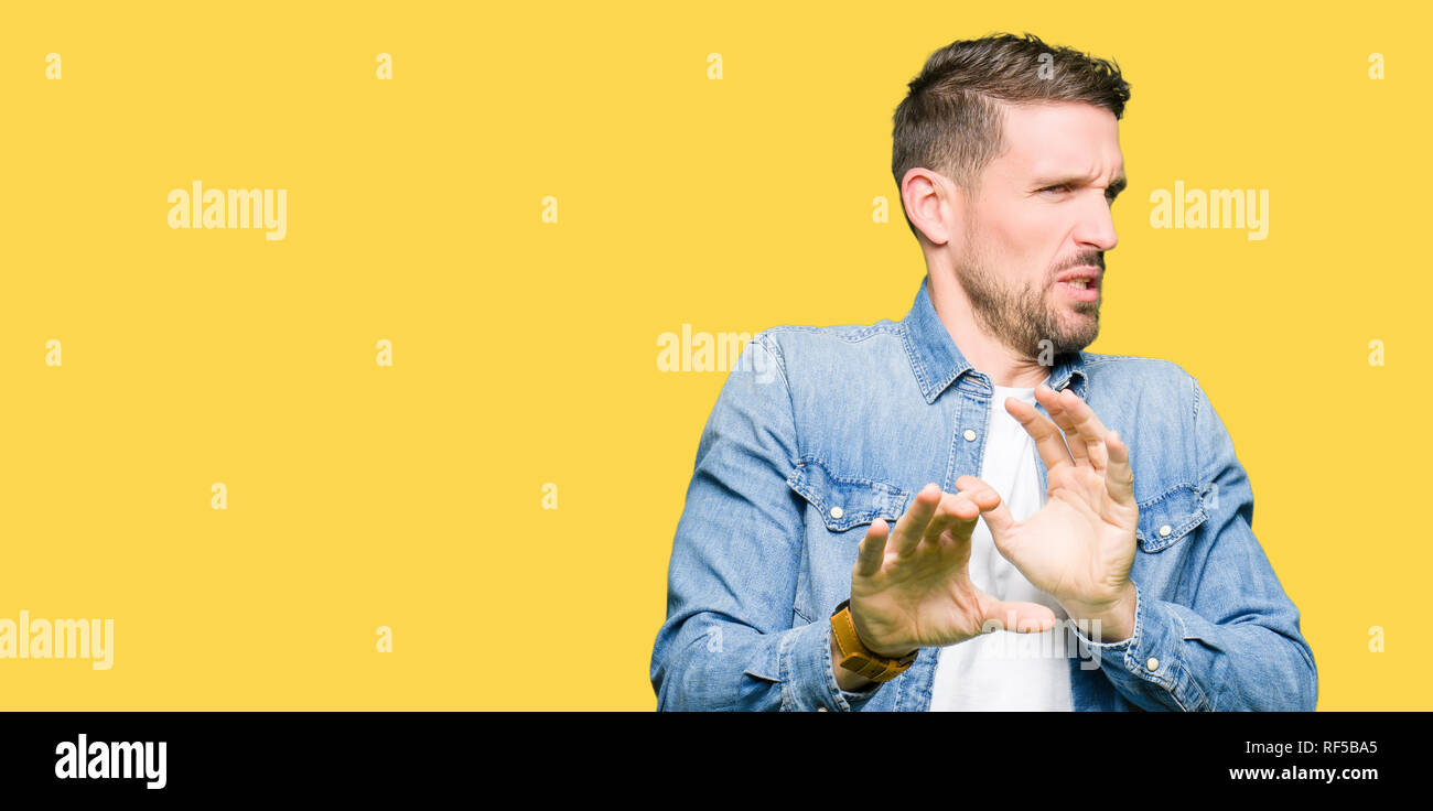 Handsome man with blue eyes and beard wearing denim jacket disgusted ...