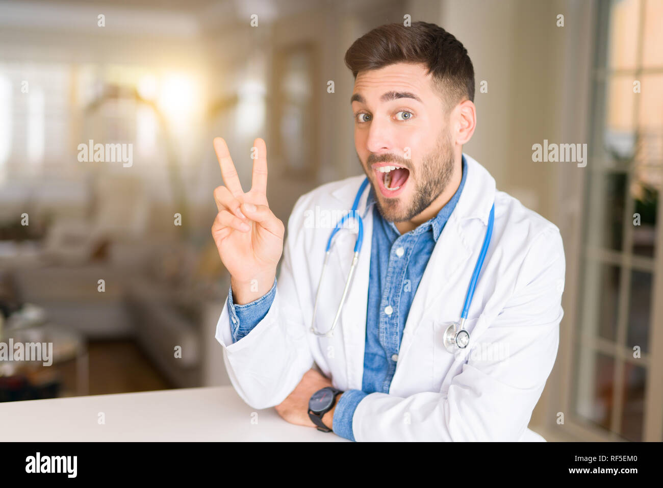 Young handsome doctor man at the clinic smiling with happy face winking ...