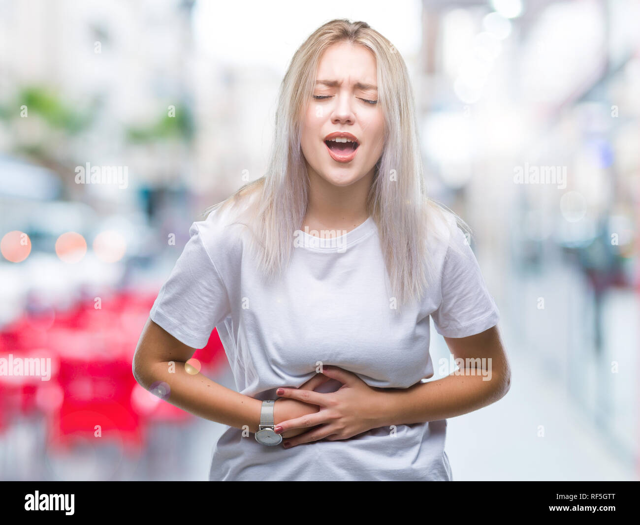 Young blonde woman over isolated background with hand on stomach ...