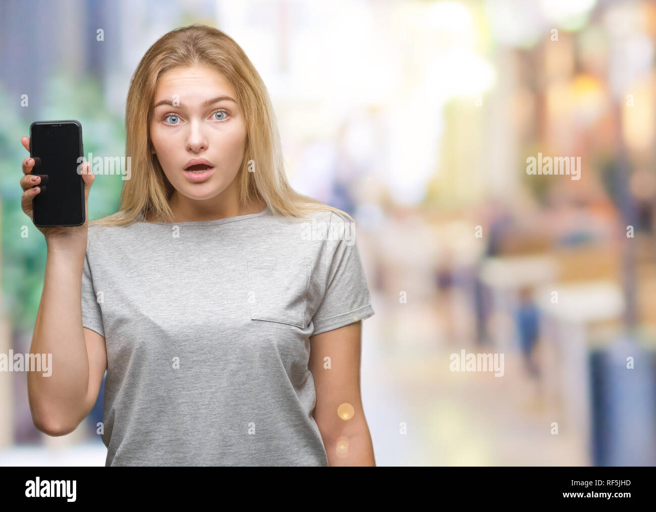 Young caucasian woman showing screen of smartphone over isolated ...