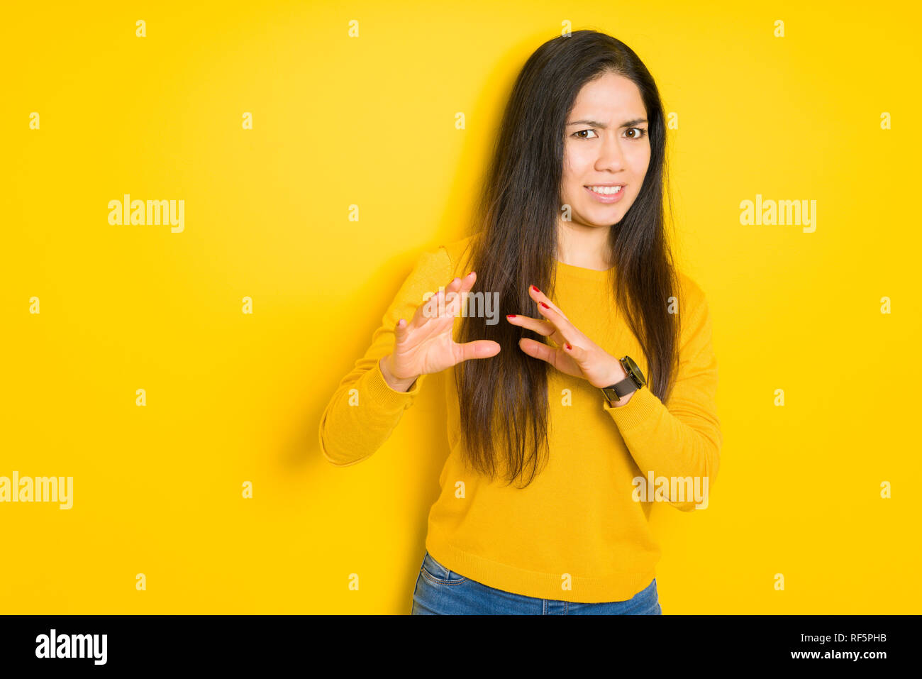 Beautiful brunette woman over yellow isolated background disgusted ...