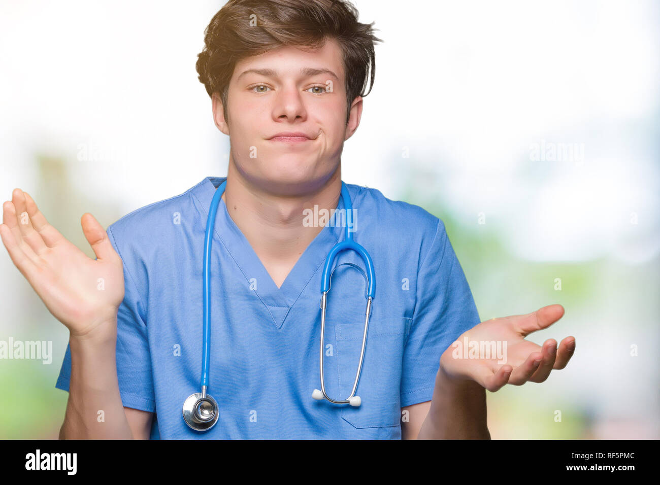Young doctor wearing medical uniform over isolated background clueless ...
