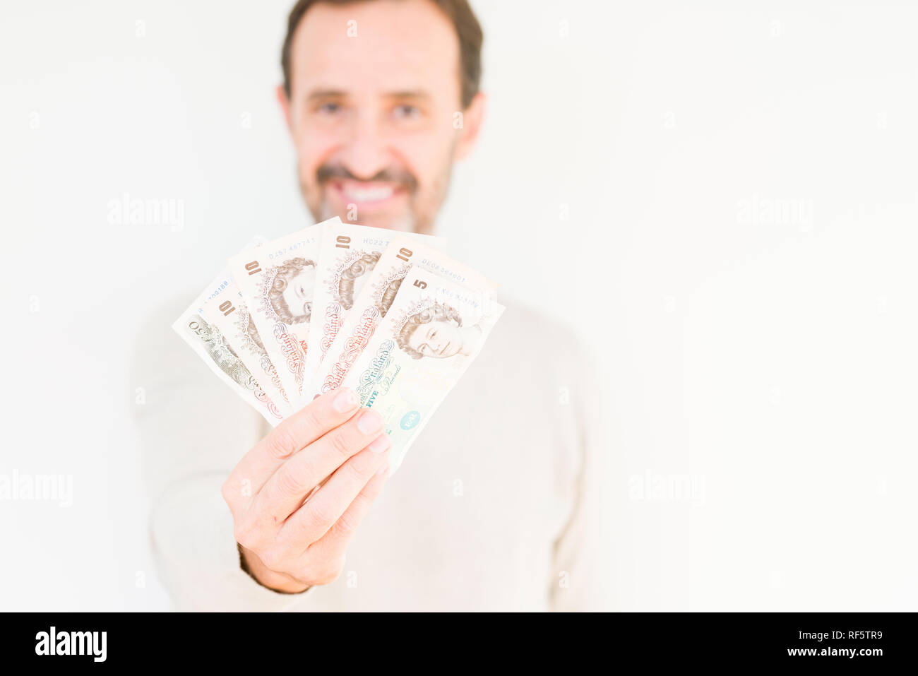 Senior man holding bunch of pounds bank note over isolated background ...
