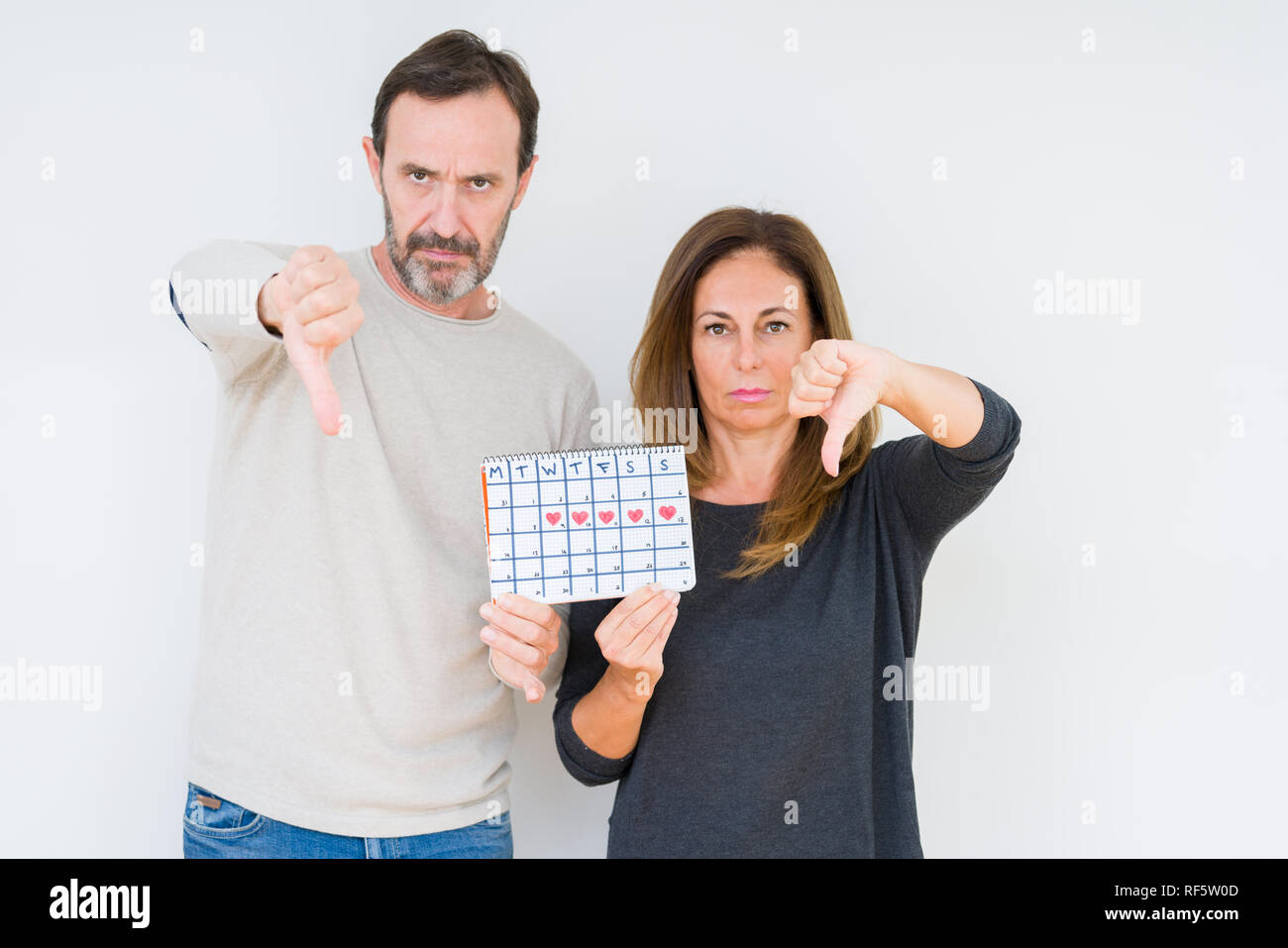 Middle age couple holding month calendar over isolated background with ...