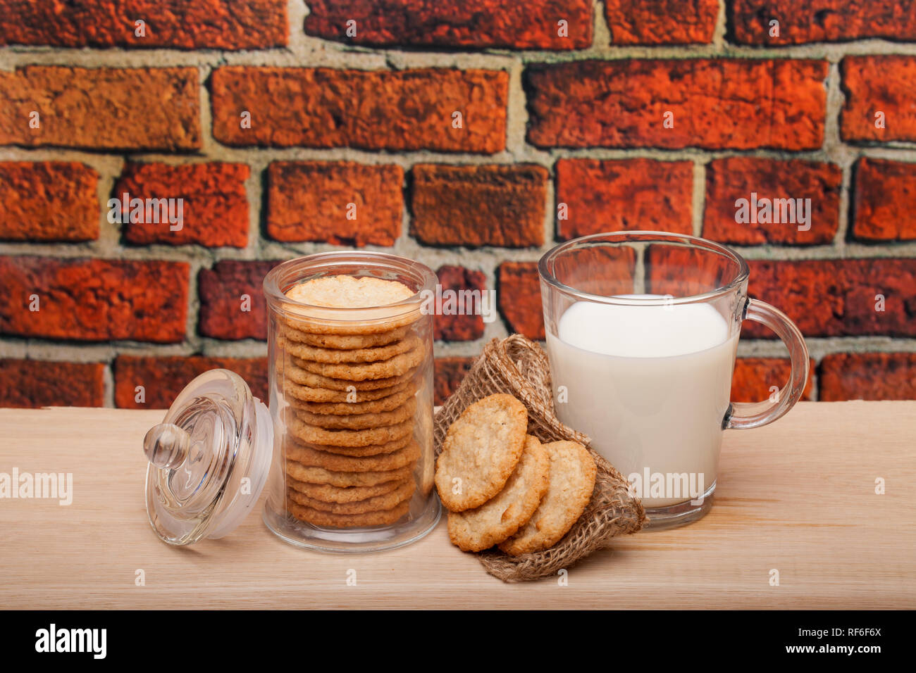 Oatmeal cookies with milk on the oak table, with brick wall Stock Photo ...