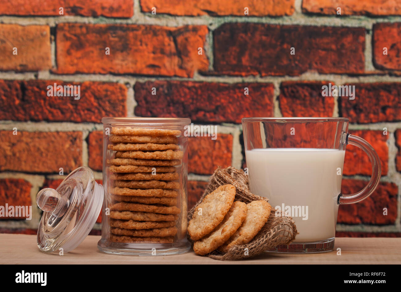 Oatmeal cookies with milk on the oak table, with brick wall Stock Photo ...
