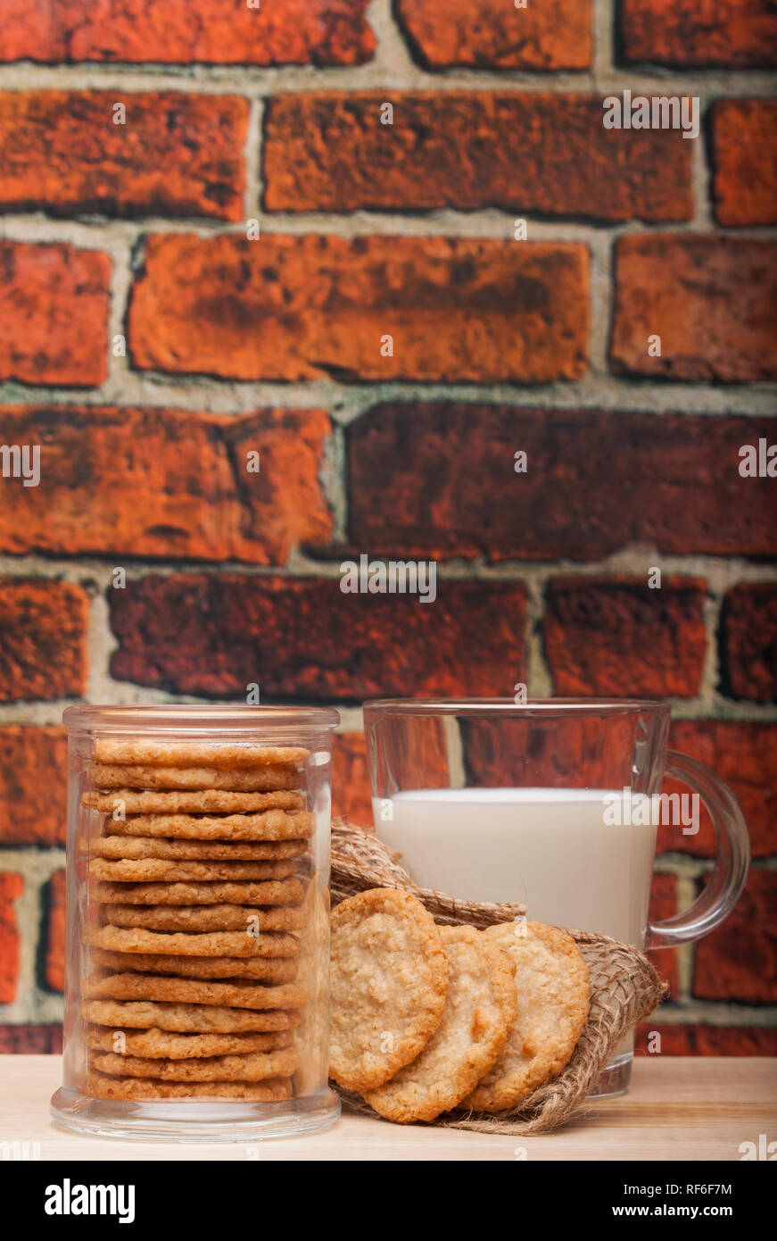 Oatmeal cookies with milk on the oak table, with brick wall Stock Photo ...