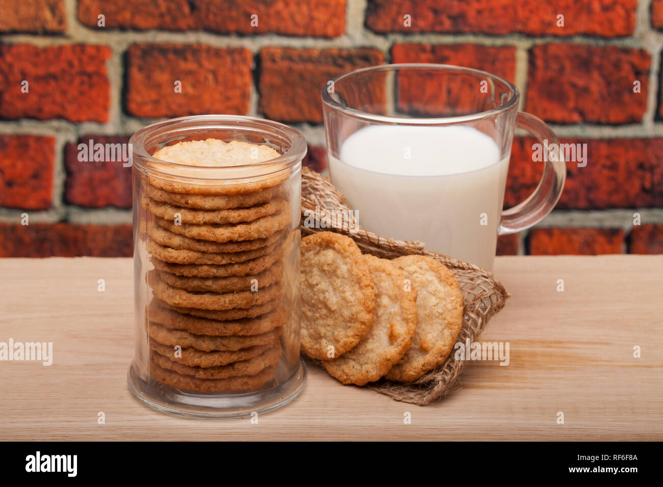 Oatmeal cookies with milk on the oak table, with brick wall Stock Photo ...