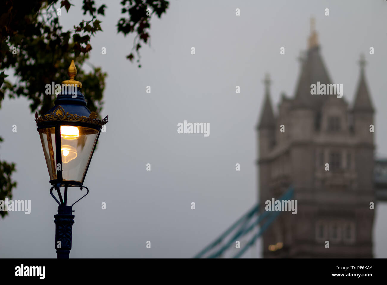 Street lantern against the Tower bridge in deep morning fog. London ...
