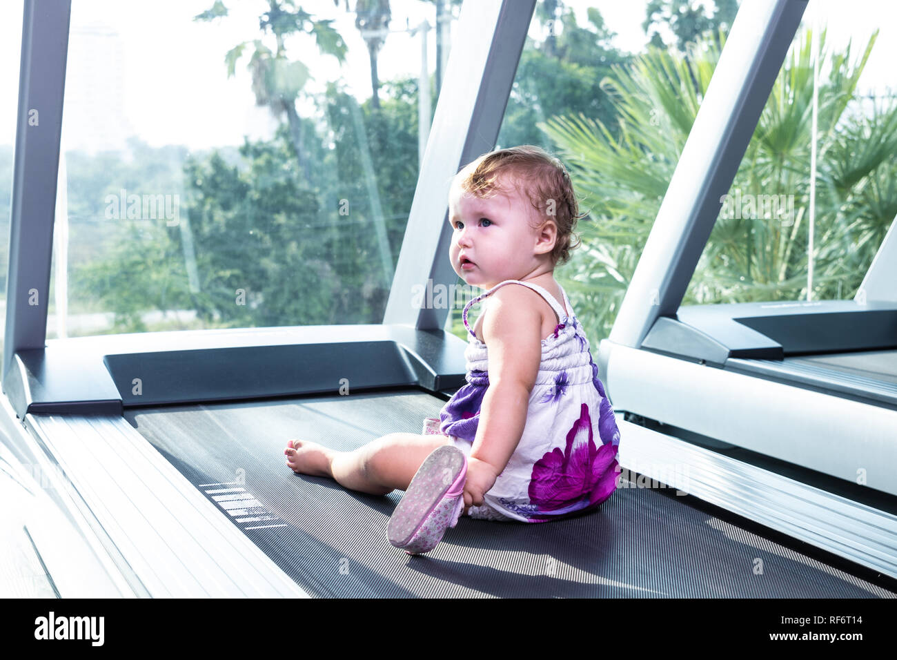 baby crawling on the treadmill in the gym with a view from the window ...
