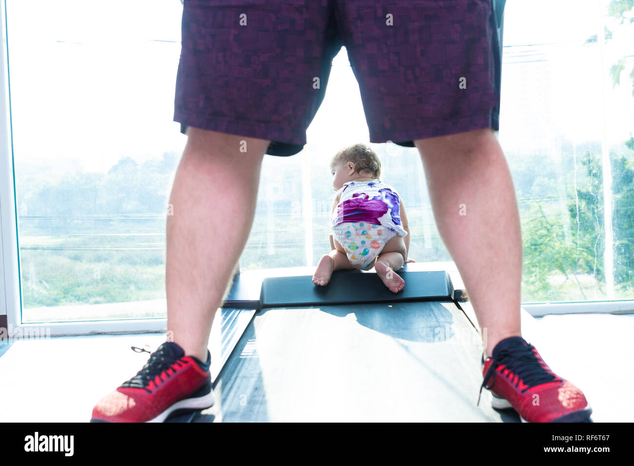 baby crawling on the treadmill in the gym with a view from the window ...